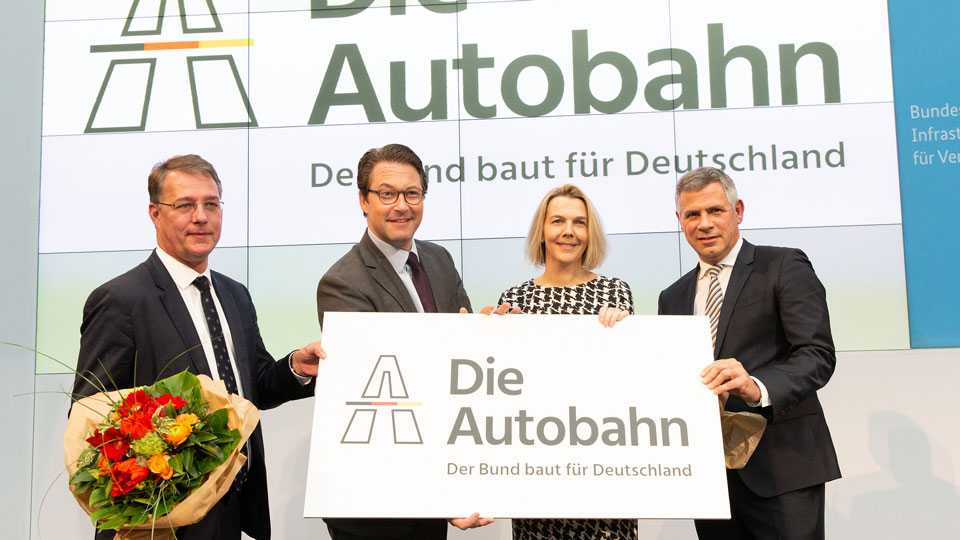 Führungsmannschaft und Logo der Autobahn GmbH des Bundes stehen - DVZ